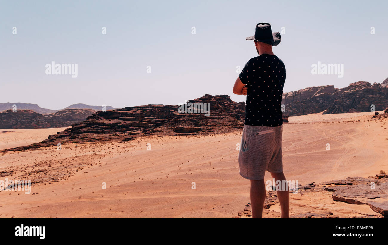 a tourist looks out over the vast red sand landscape of the Wadi Rum ...