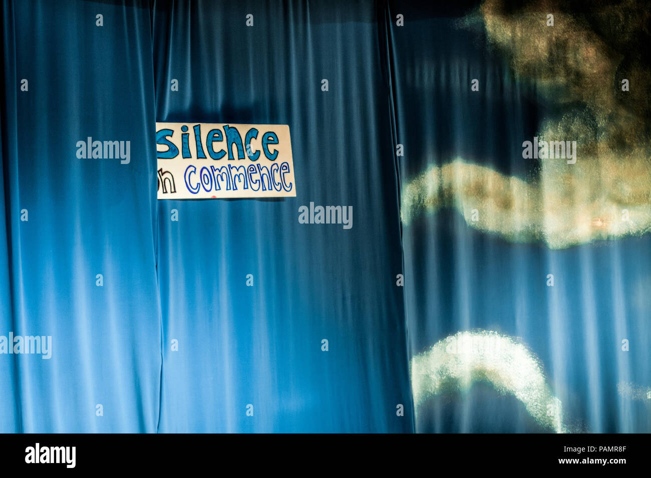 French sign that says "Silence, it starts", on a blue curtain ...