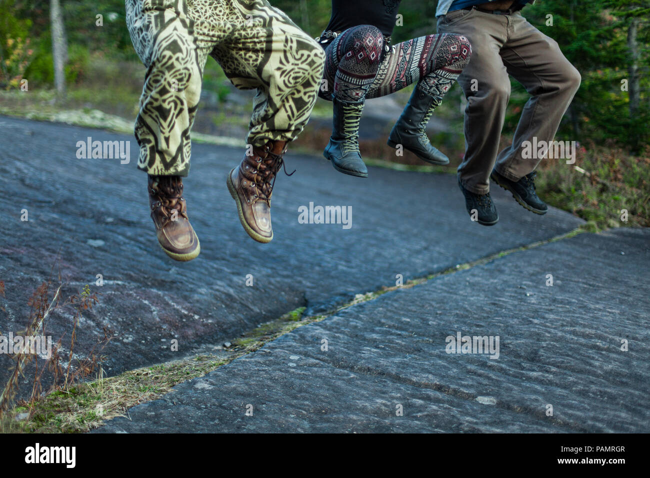 Three people jumping high in the air from a rock Stock Photo - Alamy