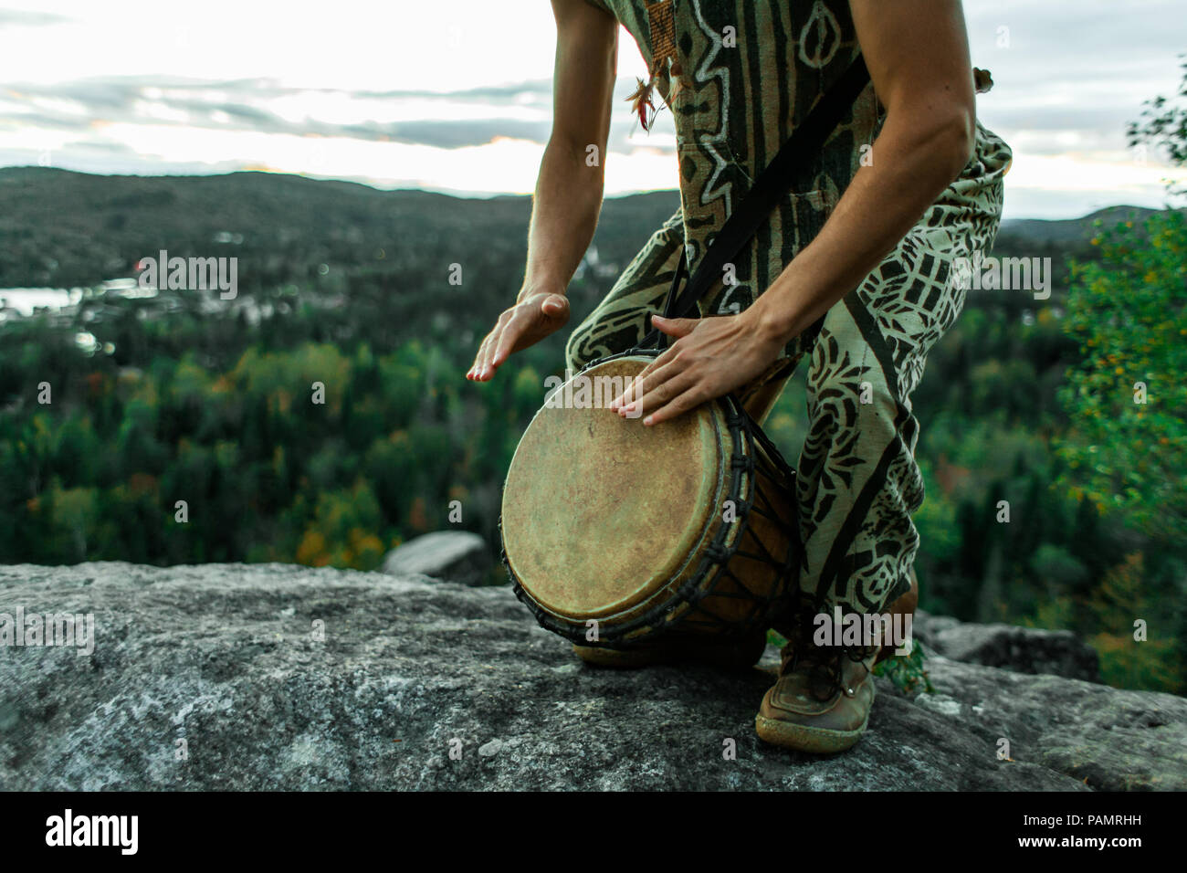 Man dressed with traditionnal clothes playing djembe on the top of a ...