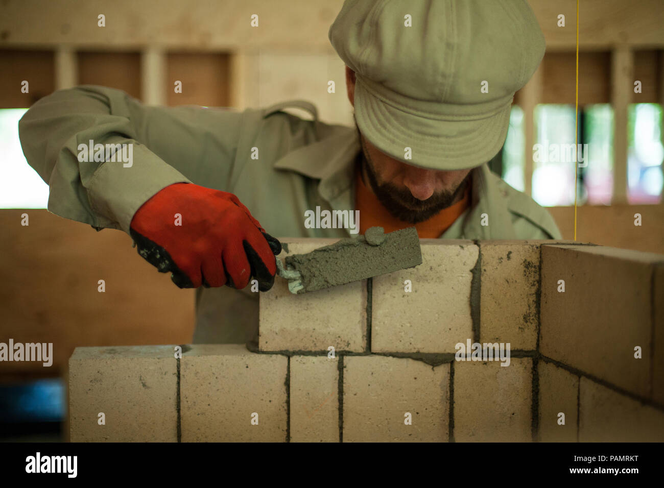 Brickmason putting ciment between brinks while building a brick wall ...