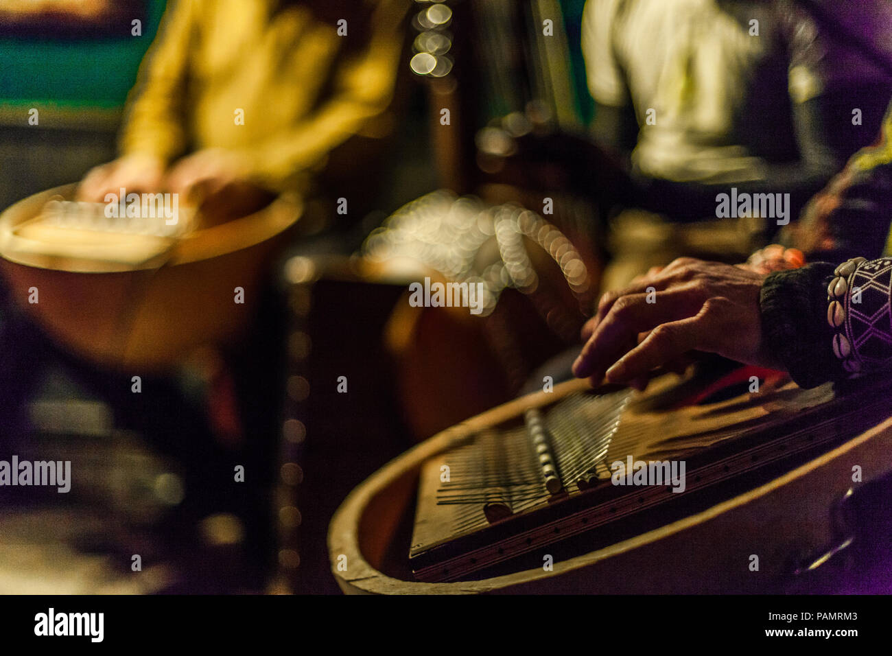 Man's hands playing kalimba with blurry musicians playing african ...