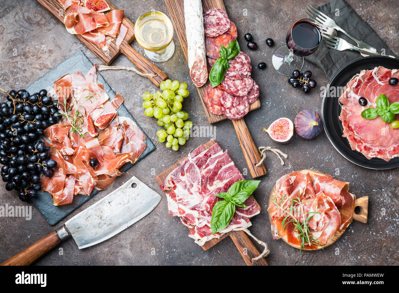 Different types jamon on cutting boardes with figs, grapes and wine ...