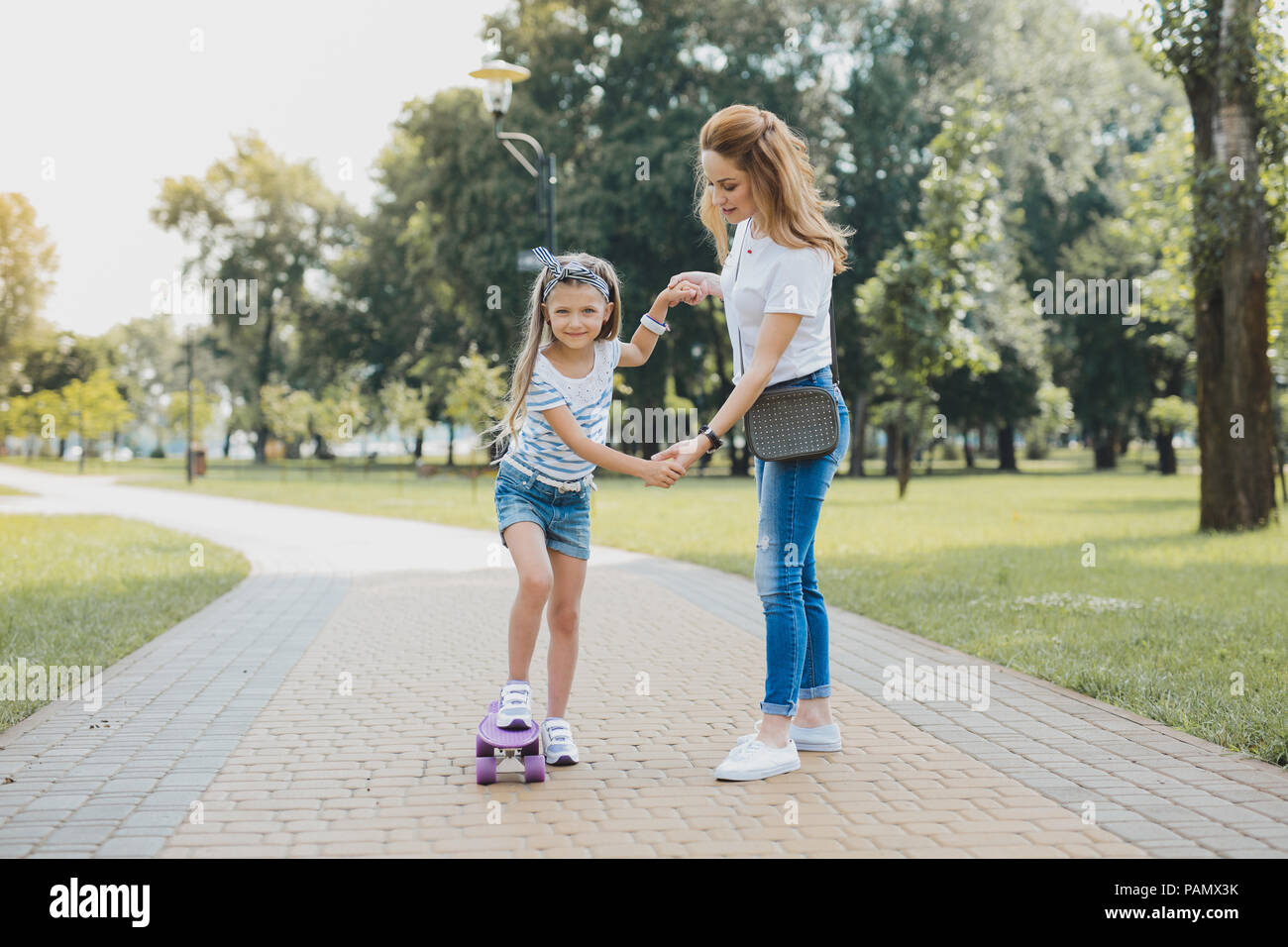 Pleasant stylish preschool girl having active walk with her mother ...