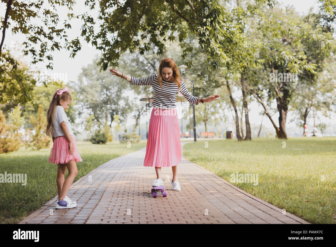 Modern mother having fun trying a ride on skateboard Stock Photo - Alamy