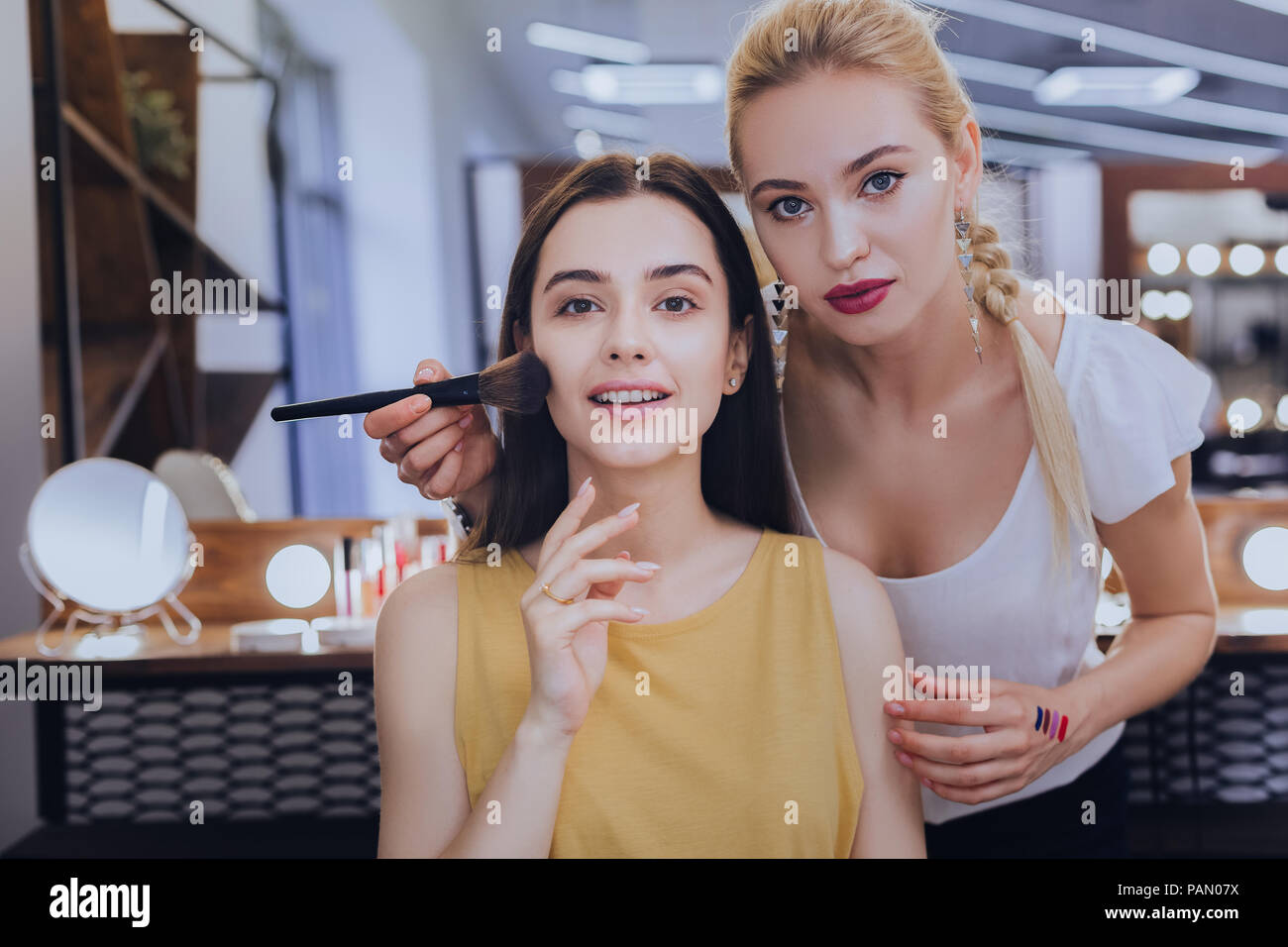 Blonde-haired makeup artist servicing her client in beauty saloon Stock ...