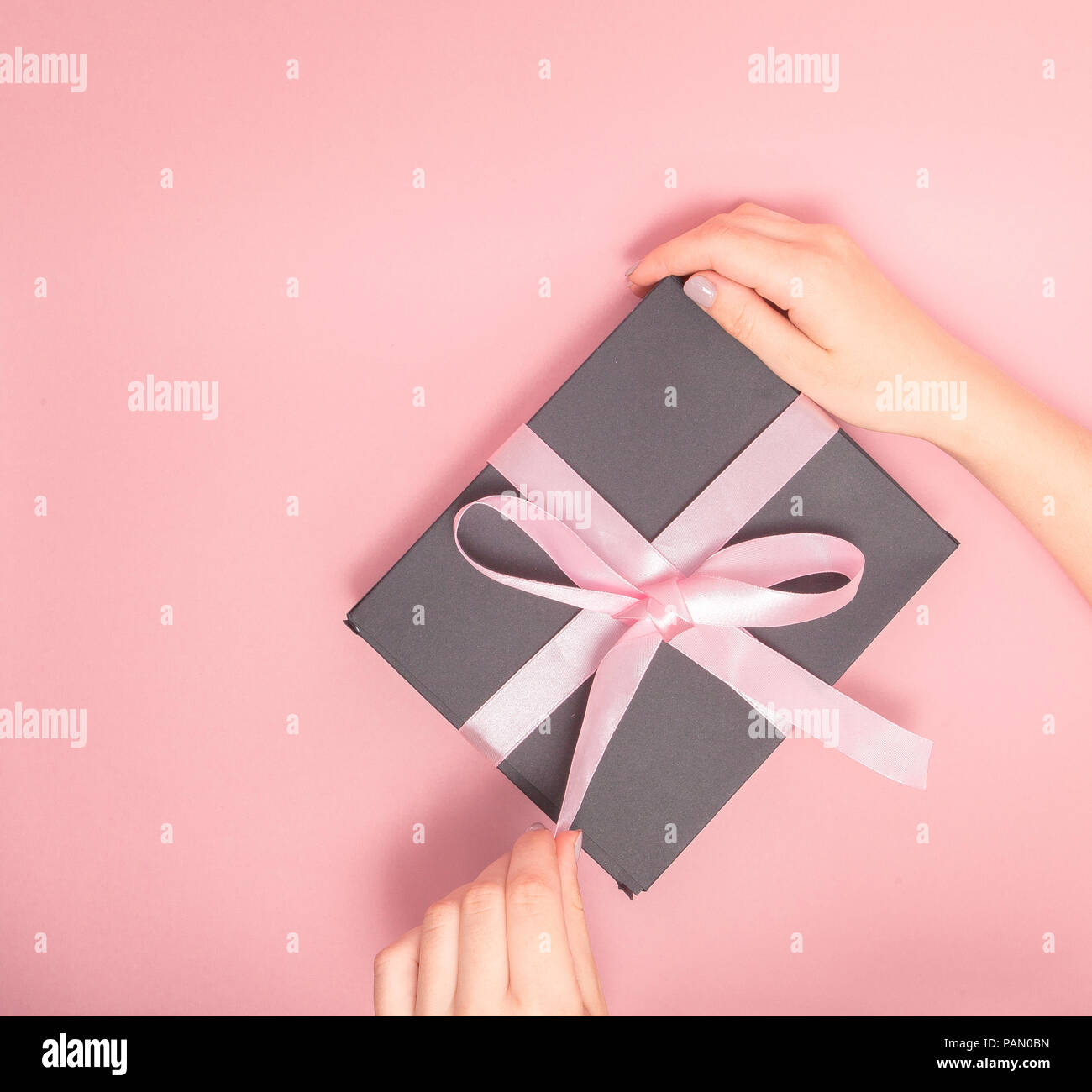 Female hands unpacking gift box. Female manicured hands going untied ...