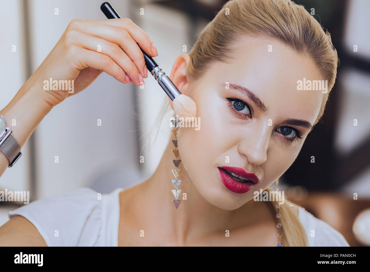 Gorgeous woman wearing silver wrist watch finishing her makeup Stock ...