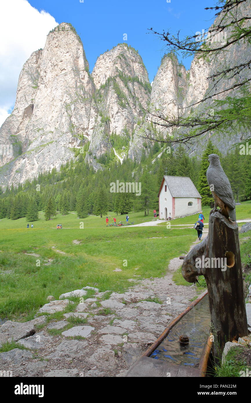 A wooden fountain with carvings along Vallunga Valley above Selva with ...