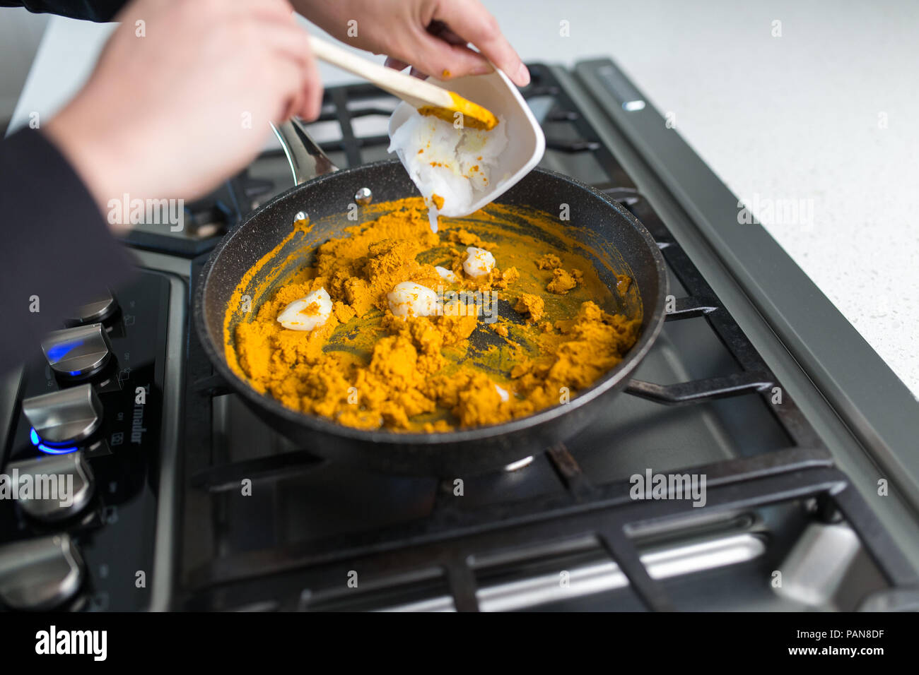 man adding ingredients to golden paste preparation Stock Photo - Alamy