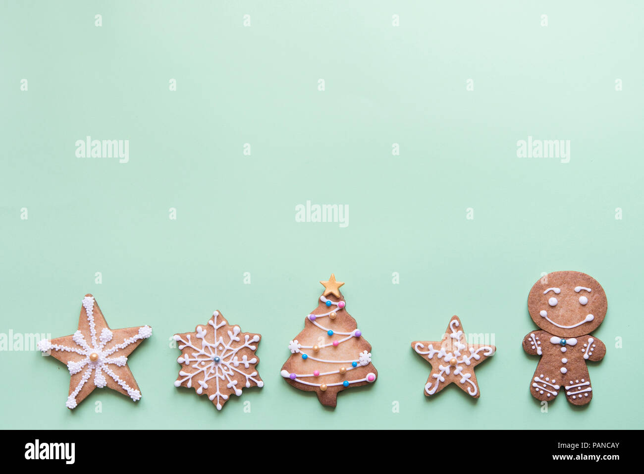 Row of five gingerbread cookies decorated with sugar icing on bright ...