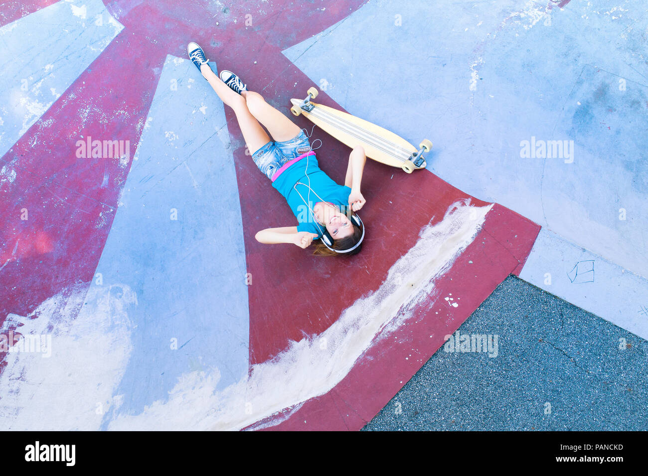 Female longboarder with earphones lying in halfpipe Stock Photo - Alamy