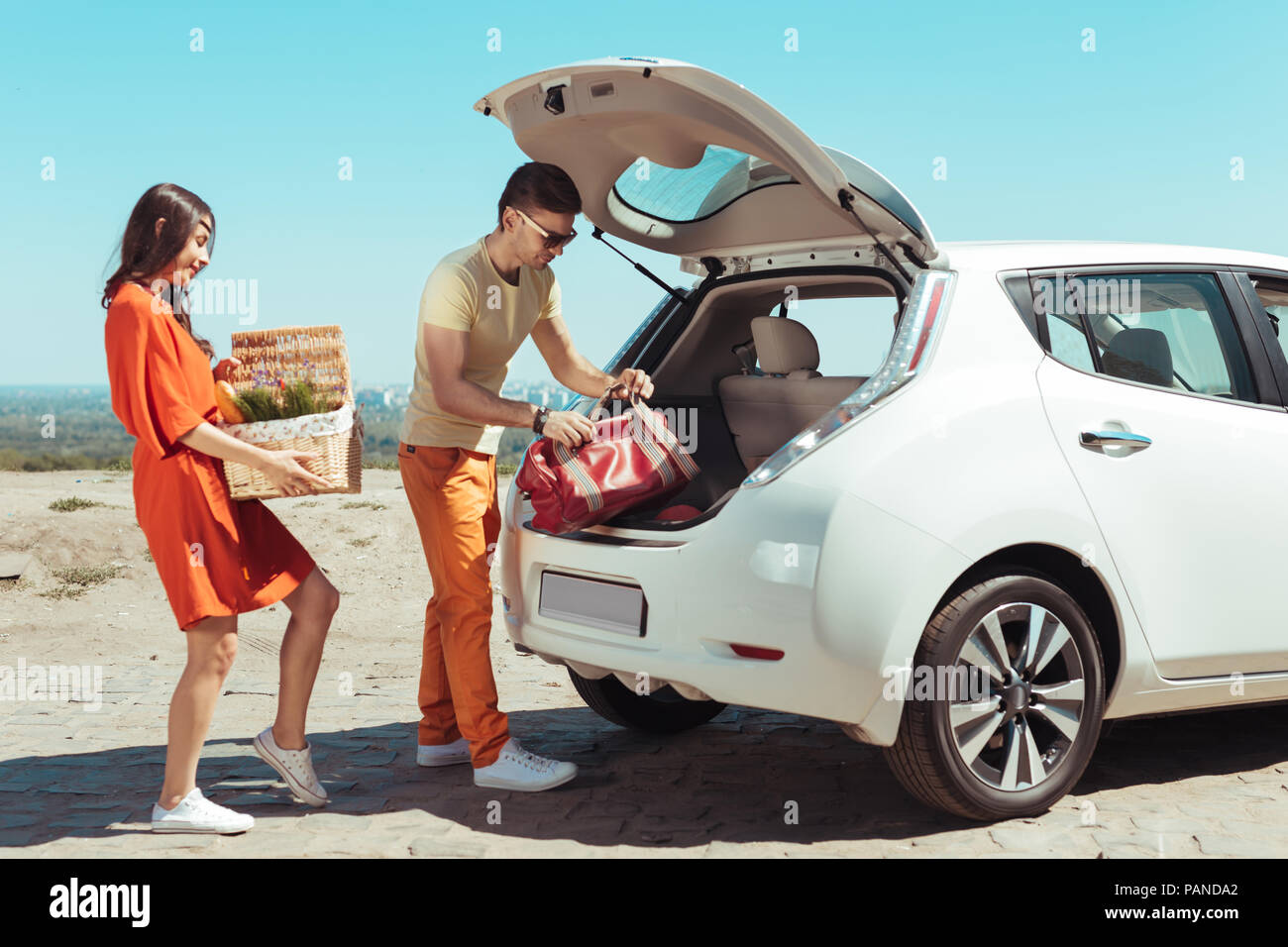 Modern couple taking their things out of car while going to picnic ...