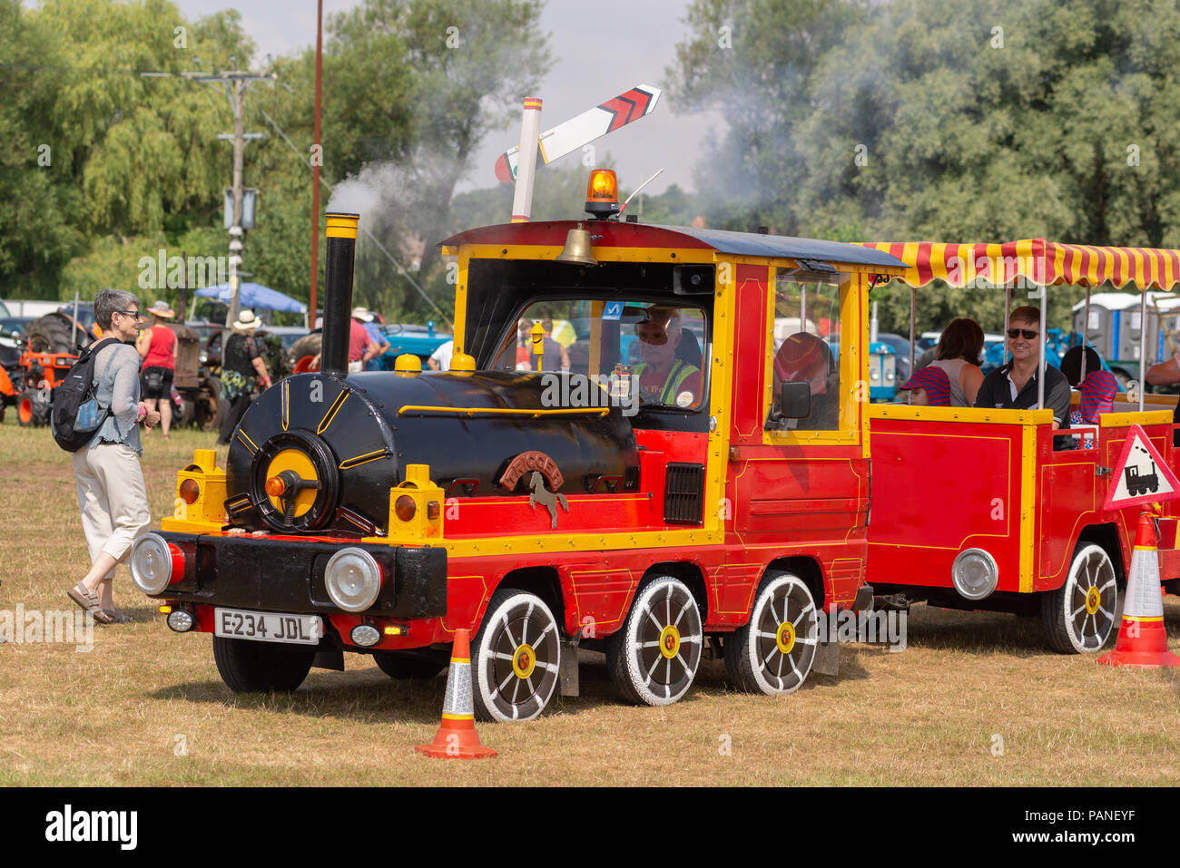 People riding a red and yellow land train at a country fair in ...