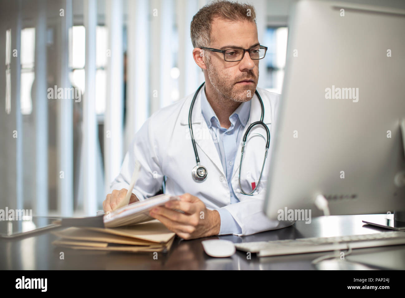 Doctor working at desk in medical practice Stock Photo - Alamy