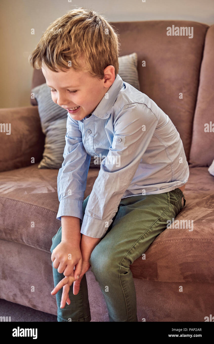 Happy boy sitting on couch Stock Photo - Alamy