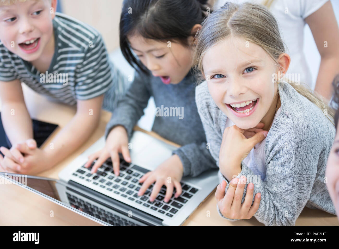 Happy pupils using laptop in class Stock Photo - Alamy