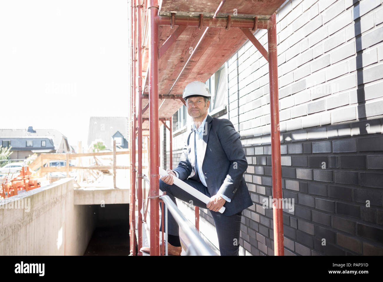Architect wearing hard hat standing on scaffolding on construction site ...