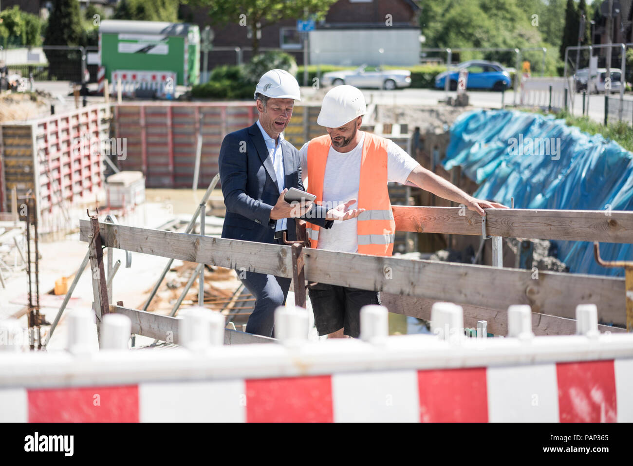 Man in suit with tablet talking to construction worker on construction ...