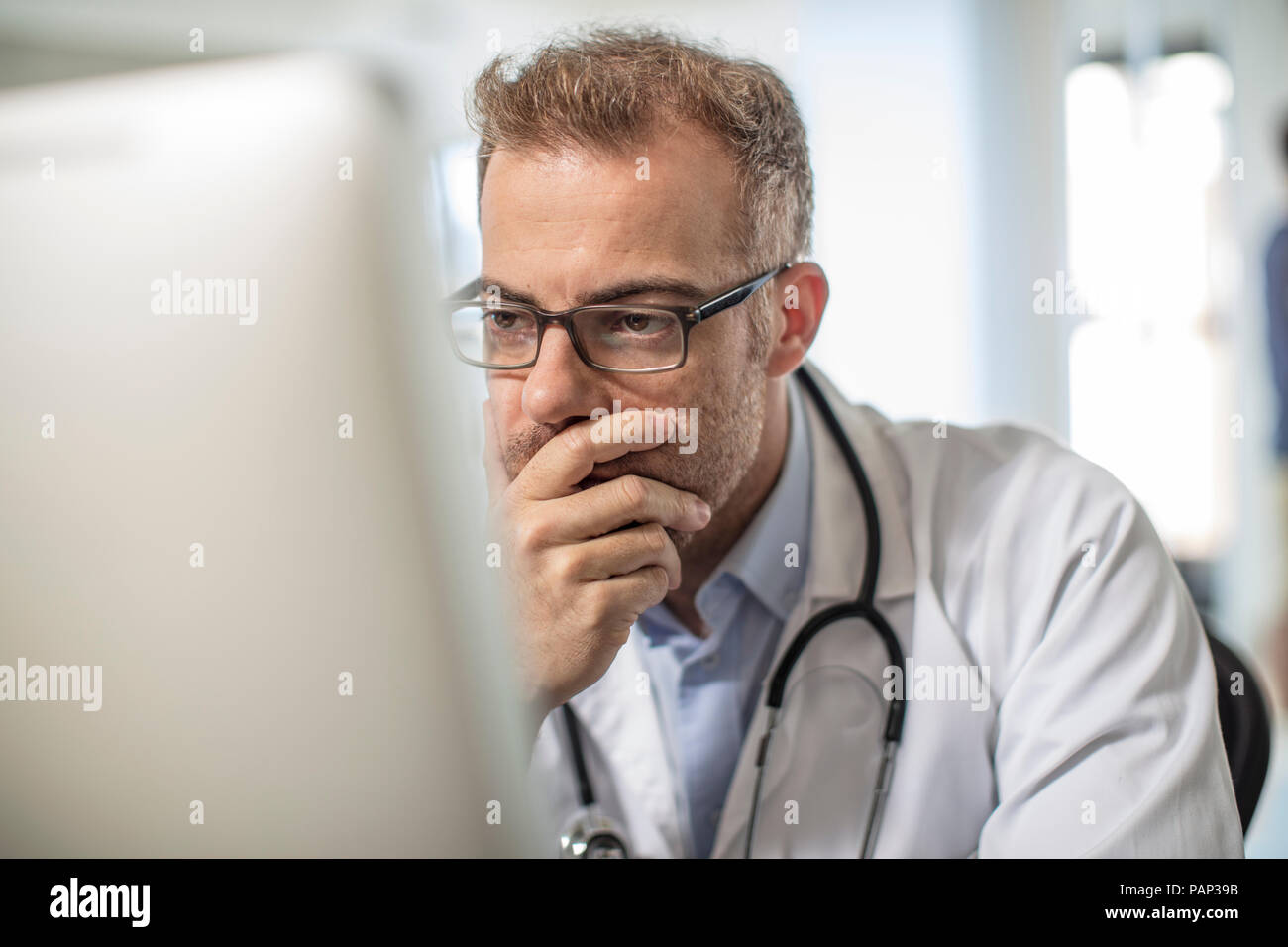 Doctor sitting at desk working on computer Stock Photo - Alamy