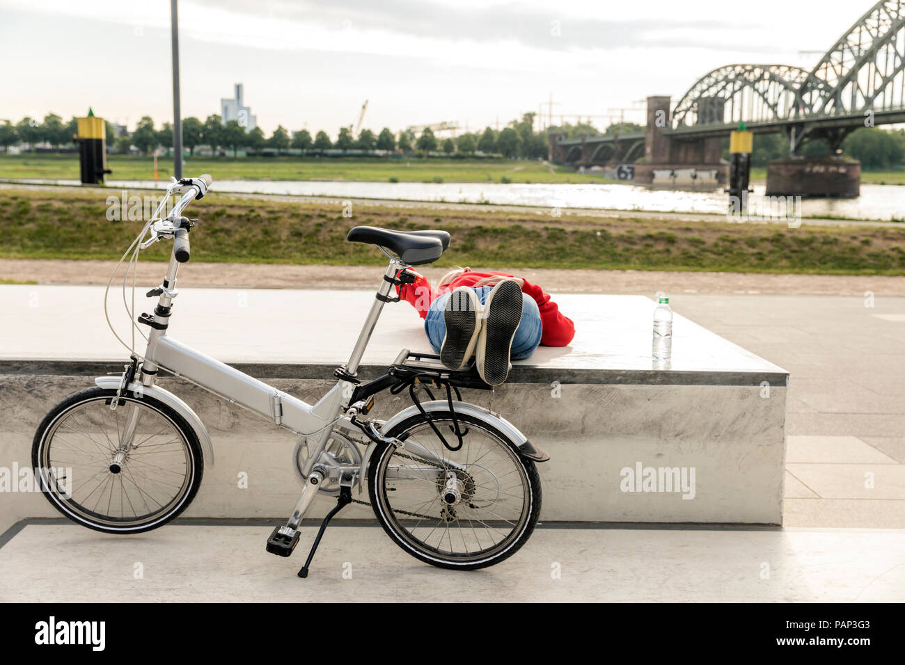 Senior woman with city bike having a break lying on platform Stock ...