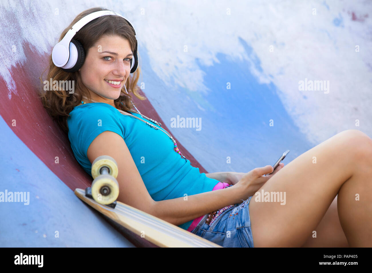 Female longboarder with earphones lying in halfpipe Stock Photo - Alamy