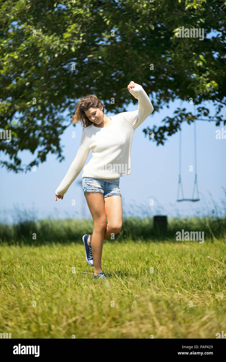 Young woman jumping around on meadow Stock Photo - Alamy