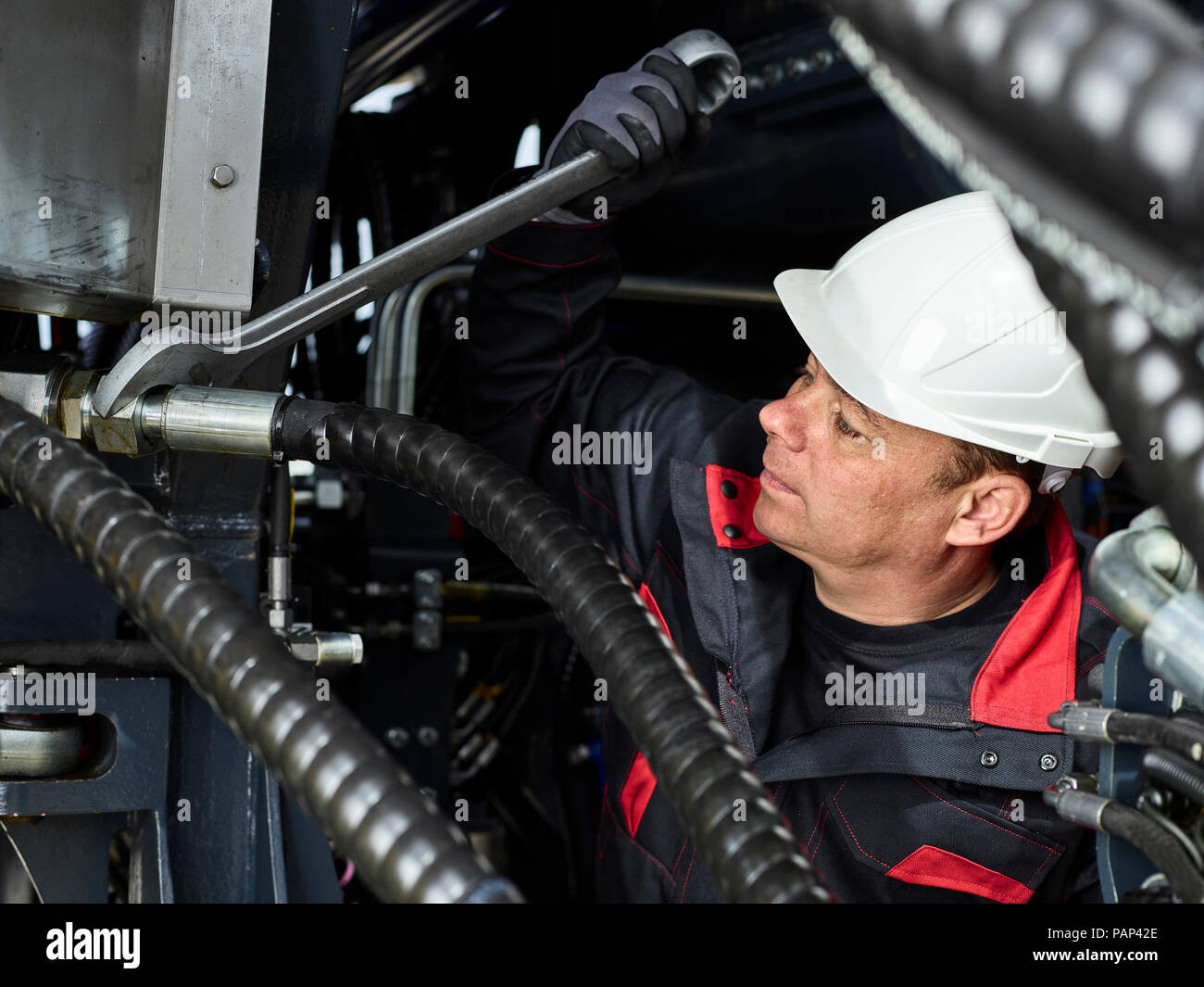 Worker fixing hose line with screw wrench Stock Photo - Alamy
