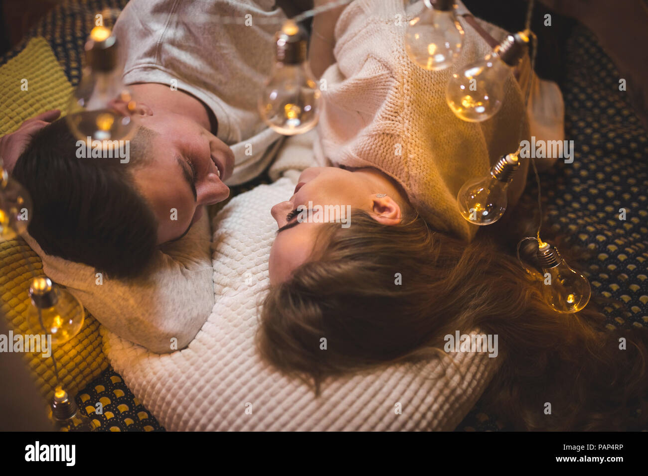 Romantic young couple cuddling in bed with fairy lights Stock Photo - Alamy
