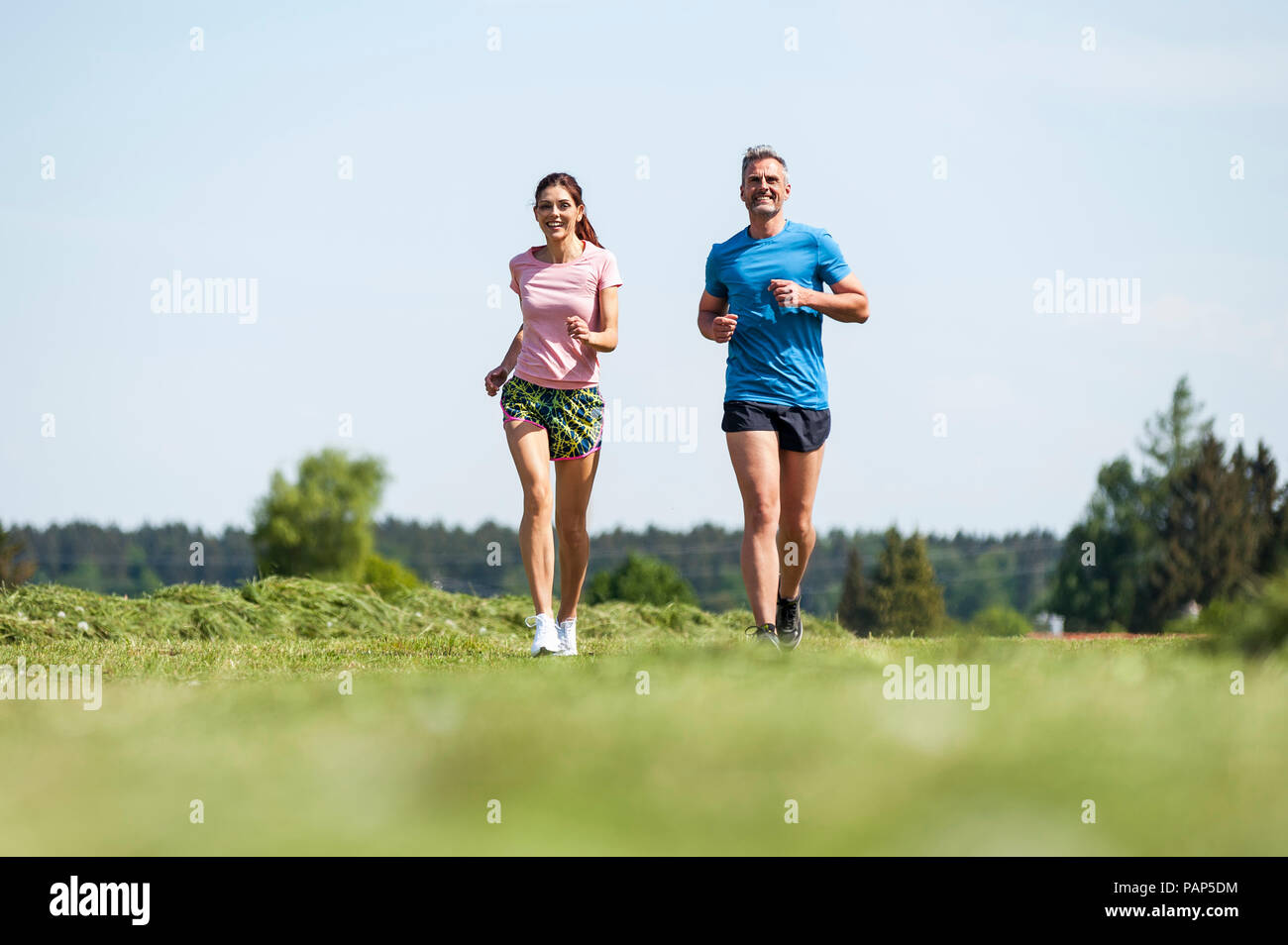 Couple running on field path Stock Photo - Alamy