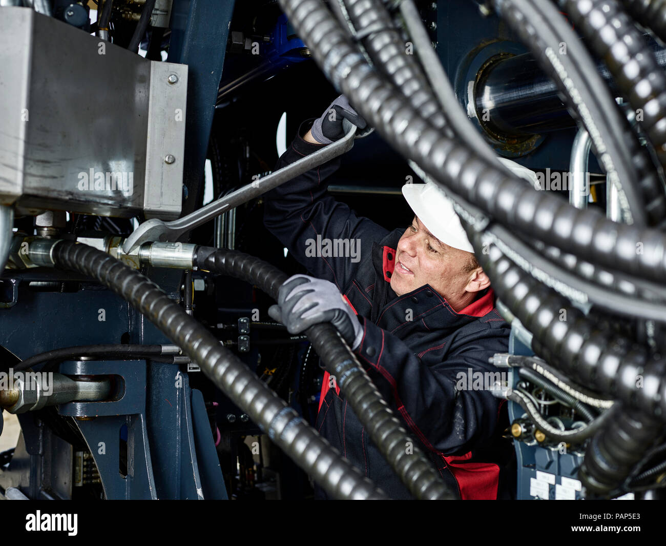 Worker fixing hose line with screw wrench Stock Photo - Alamy
