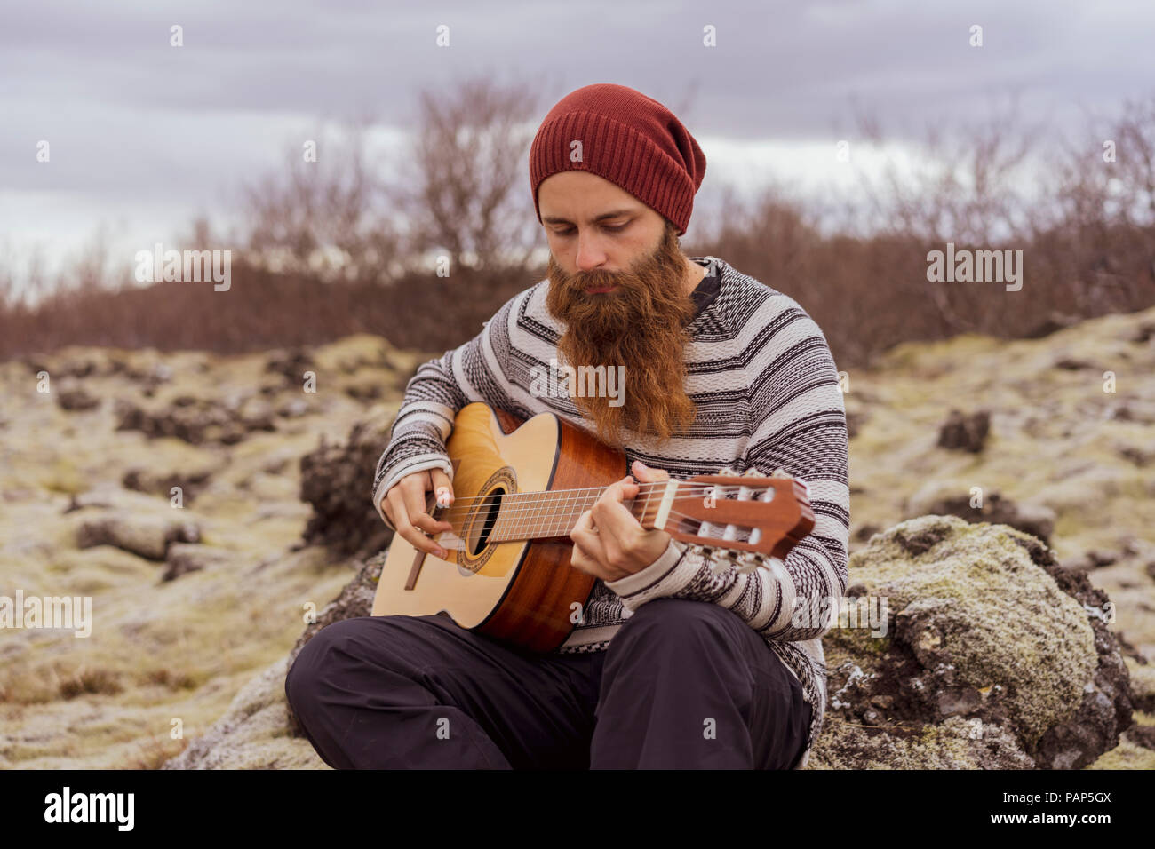 Man sitting in wilderness, playing the guitar Stock Photo - Alamy