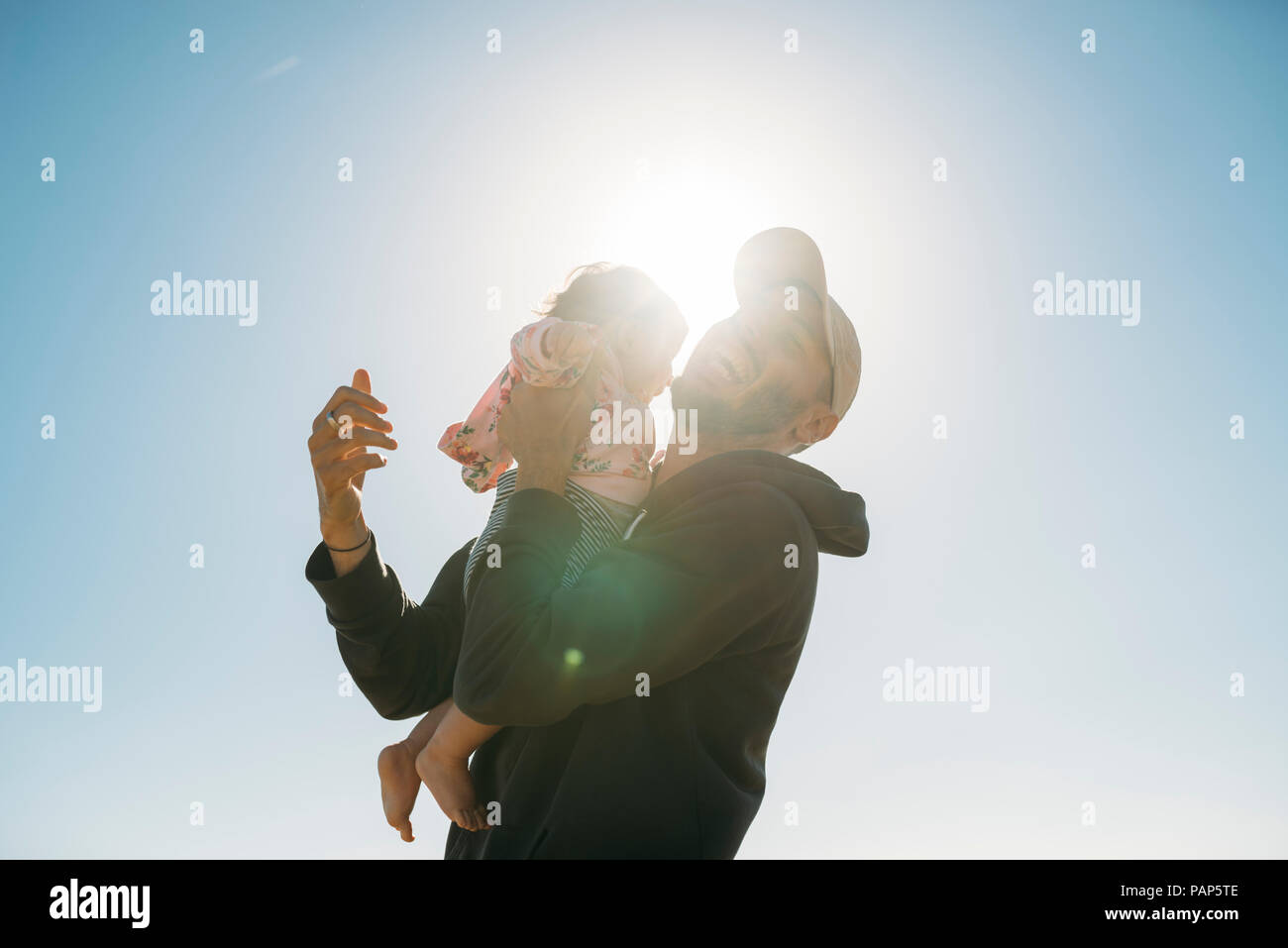 Laughing father holding baby girl at backlight Stock Photo - Alamy