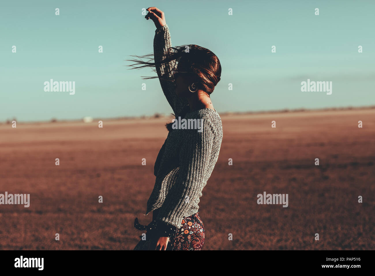 Young woman with windswept hair standing in desert landscape Stock ...