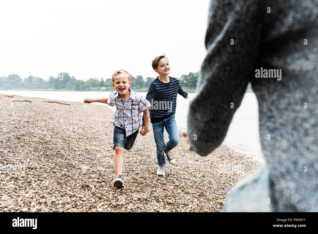 Happy boys running towards father at the riverside Stock Photo - Alamy