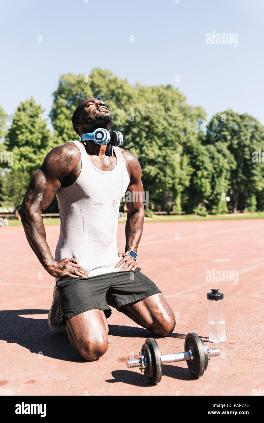 Young athlete doing weight training with dumbbells on sports field ...