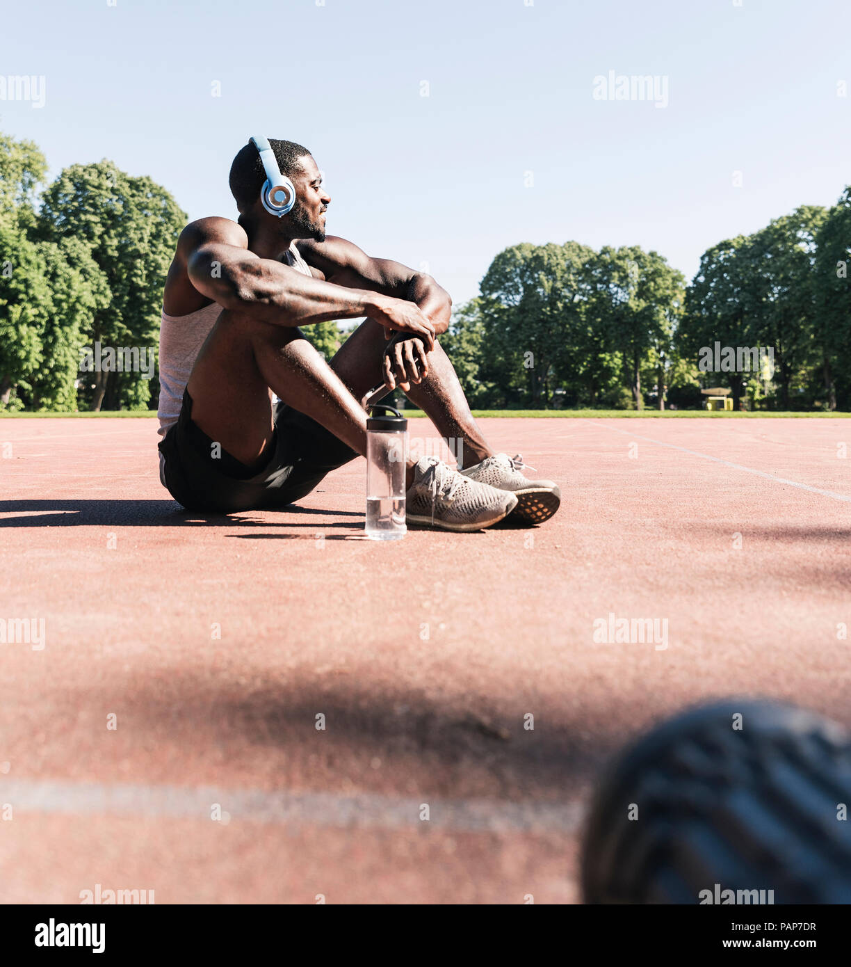 Young athlete sitting on sports field, listening music Stock Photo - Alamy