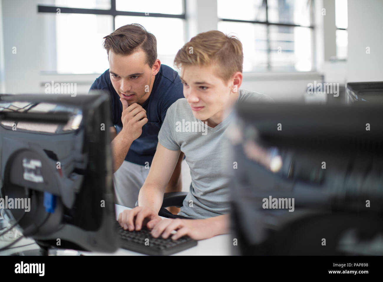 Teacher and student using computer in class Stock Photo - Alamy
