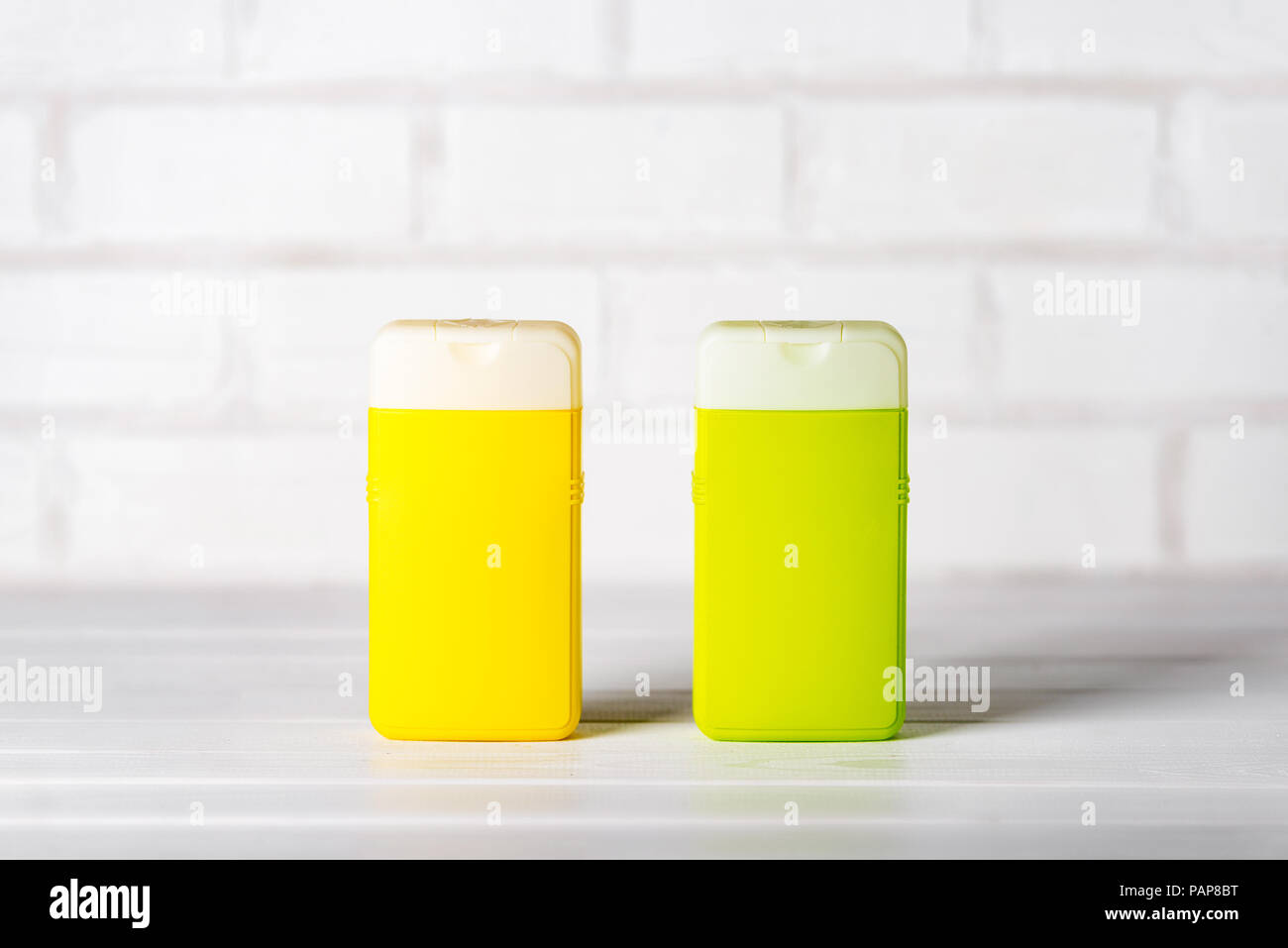 Two closed plastic shampoo and conditioner containers, green and yellow ...