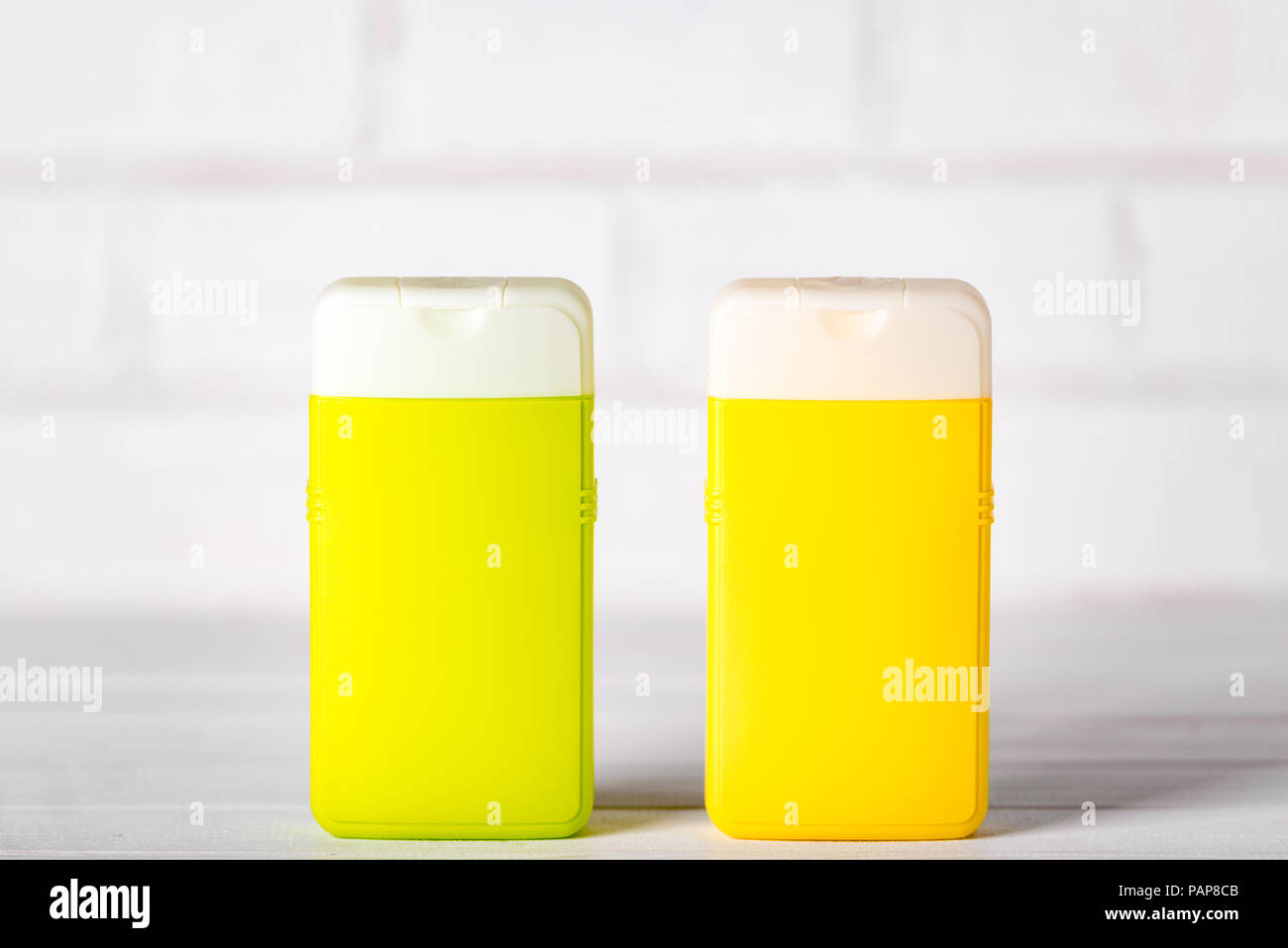 Two closed plastic shampoo and conditioner containers, green and yellow ...