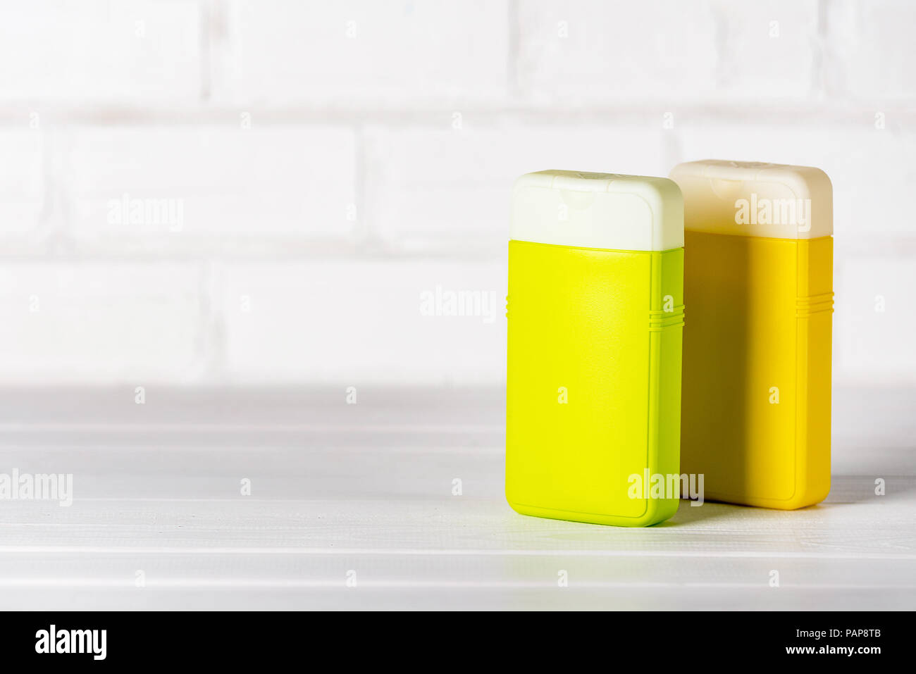 Two closed plastic shampoo and conditioner containers, green and yellow ...