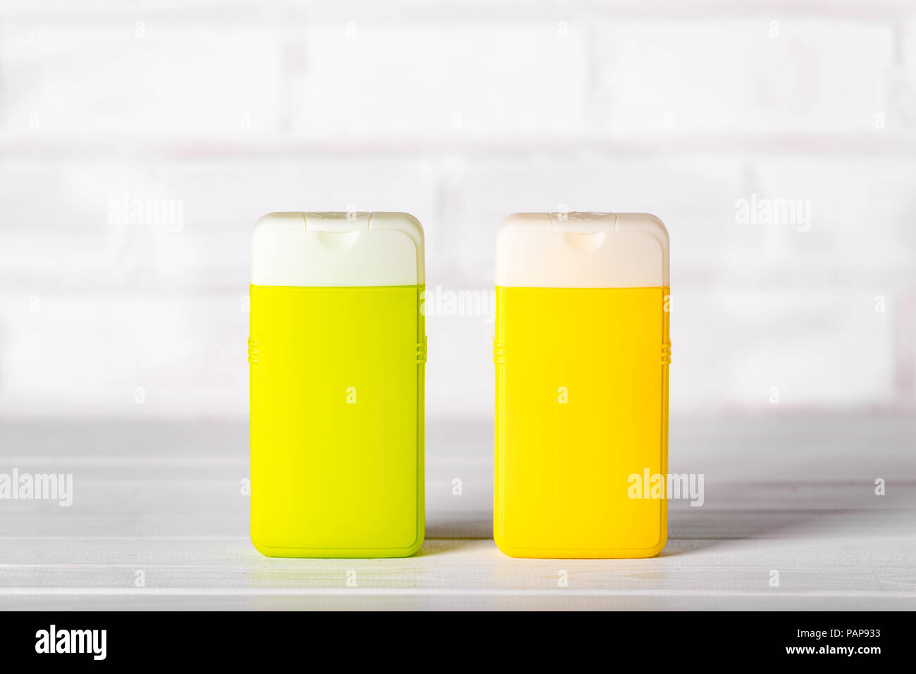 Two closed plastic shampoo and conditioner containers, green and yellow ...