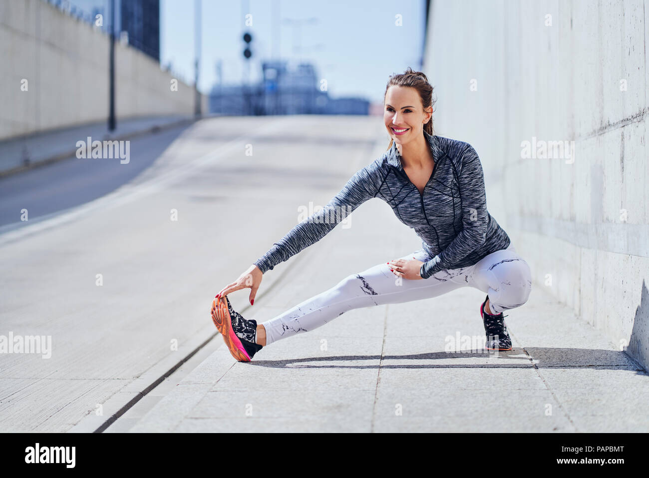 Female runner stretching legs during urban workout Stock Photo - Alamy