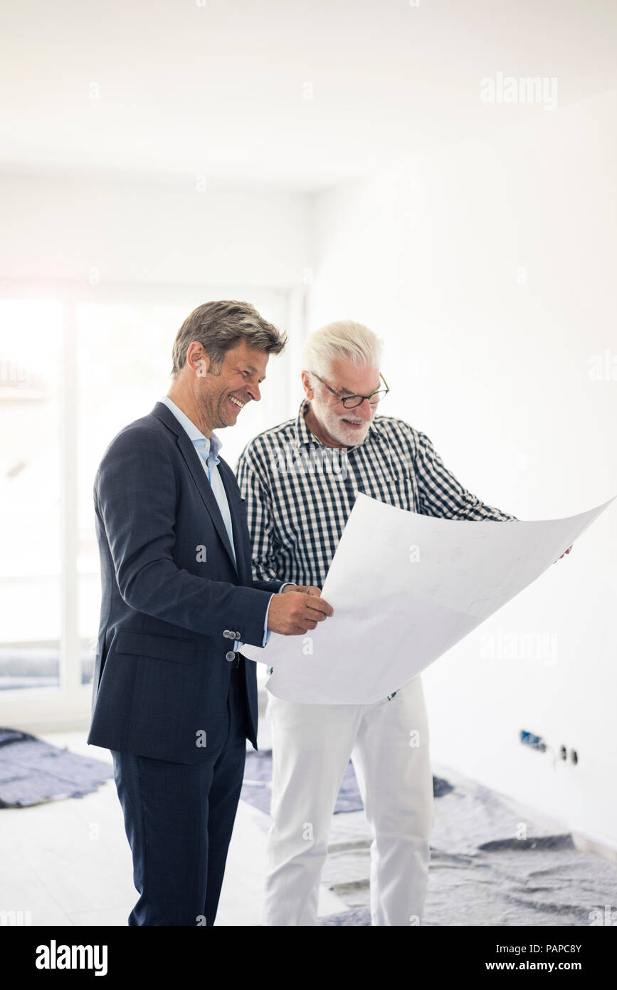 Happy man in suit and senior man looking at blueprint Stock Photo - Alamy