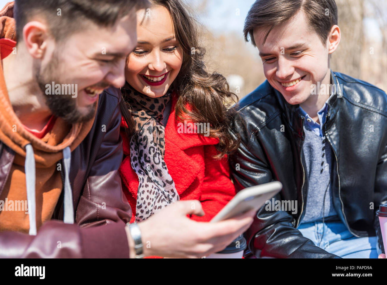 Russia, Moscow, group of friends at park, having fun together, using ...