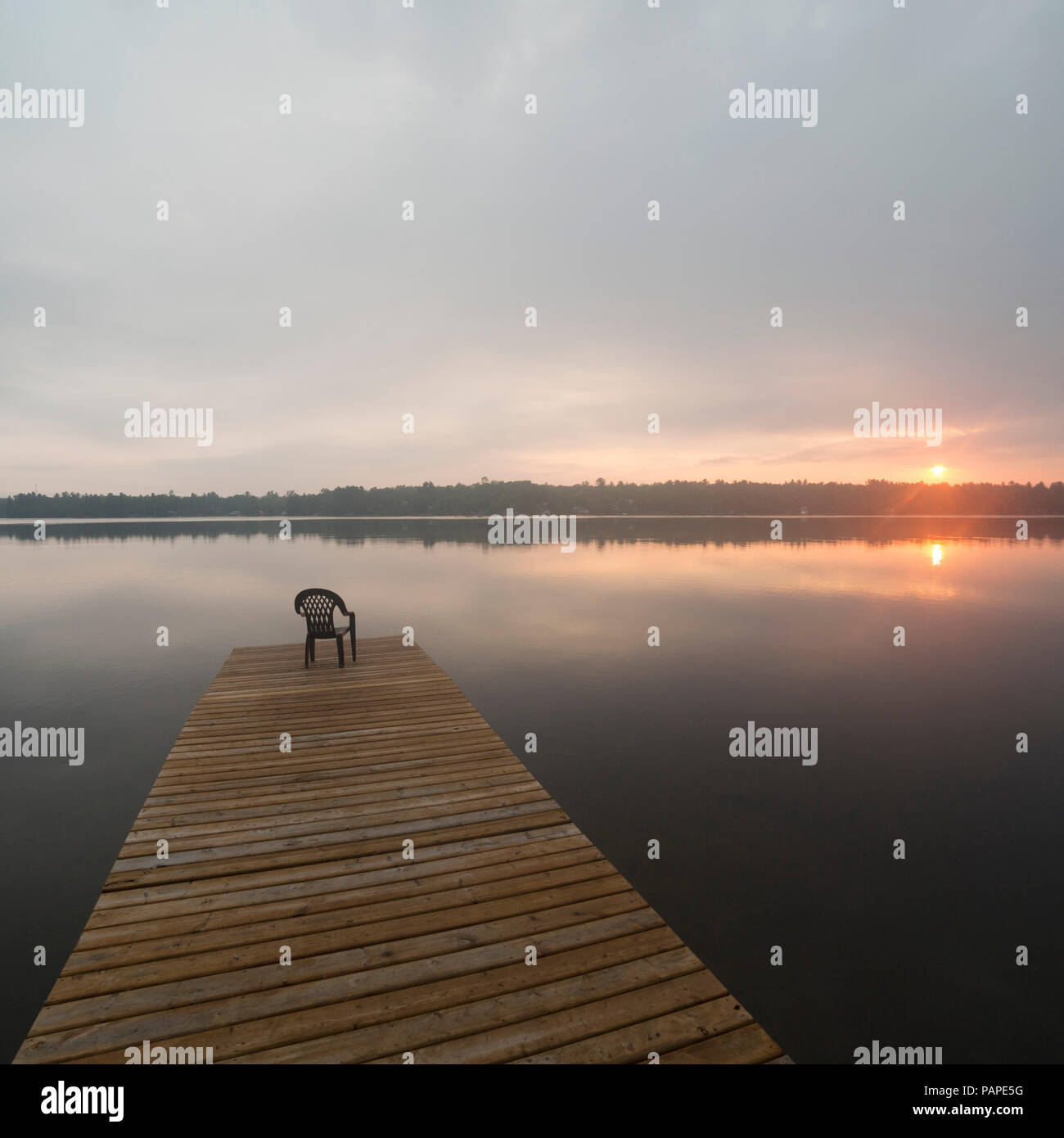 The sun rises over Gull Lake in Ontario, Canada. A pontoon jetty with a ...