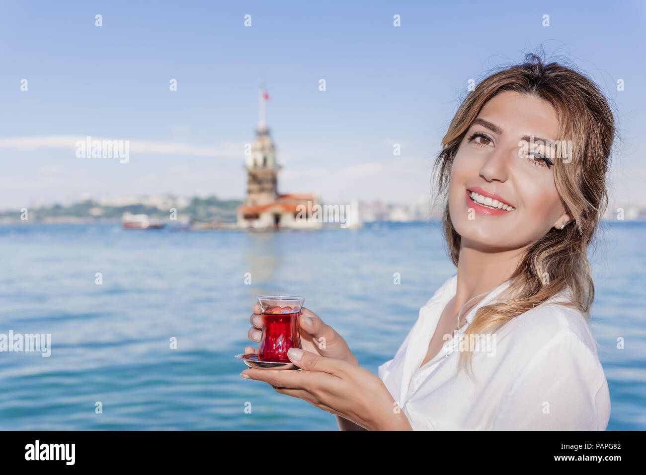 Beautiful woman traveler holds traditional Turkish tea glass in ...