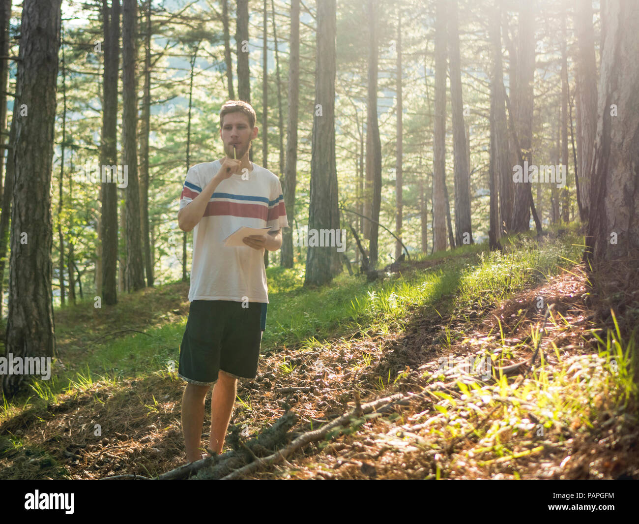 young man poet walking in the forest under the sunshine and write ...