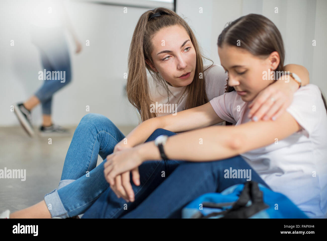 Teenage girl consoling sad friend in school Stock Photo - Alamy