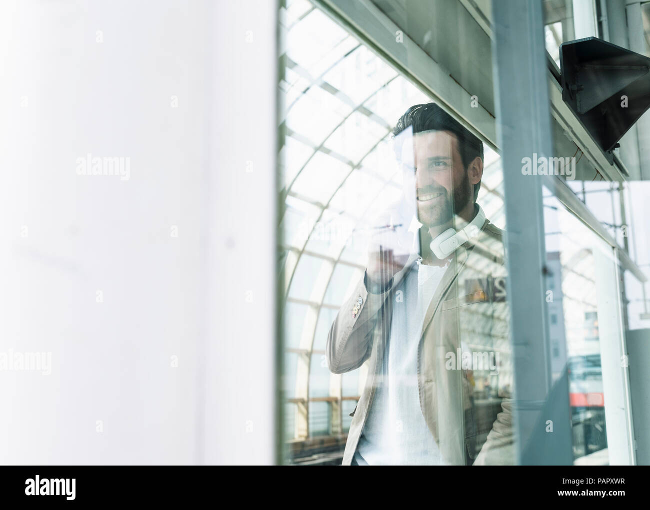 Smiling young man behind glass pane at the station platform Stock Photo ...